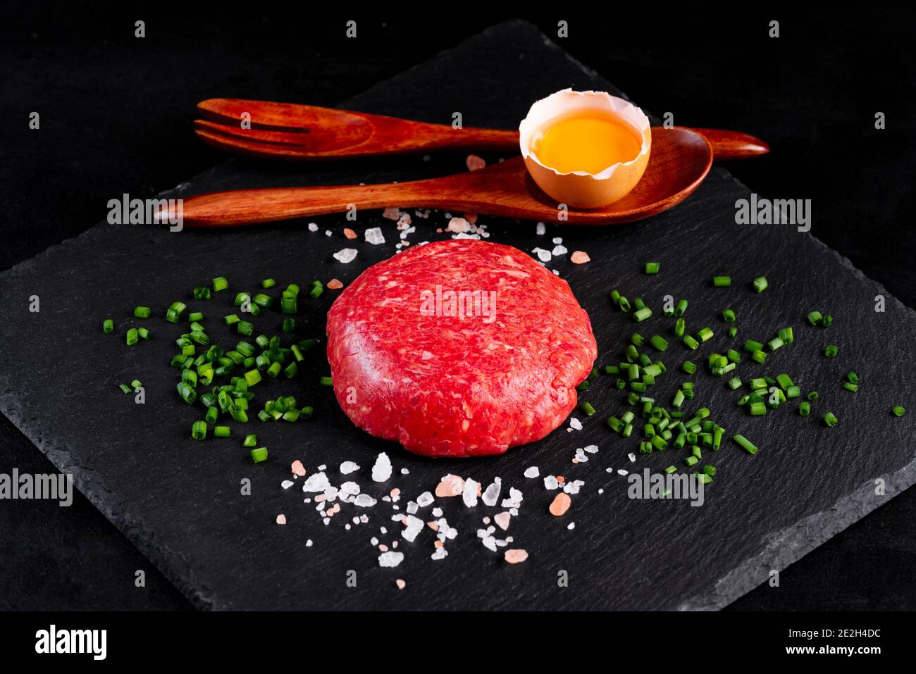 Beef tartar with egg served on a black stone plate. Tartar on a black ...