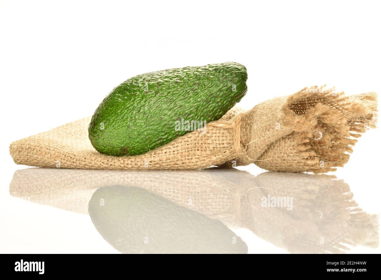 One whole oval dark green ripe, avocado, lying, on a small jute bag, on ...