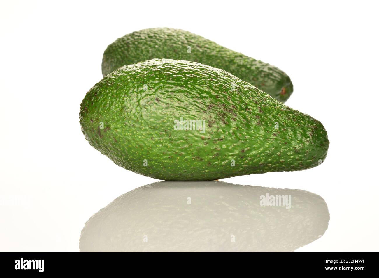Two whole oval dark green ripe organic diet avocados, lying one after ...