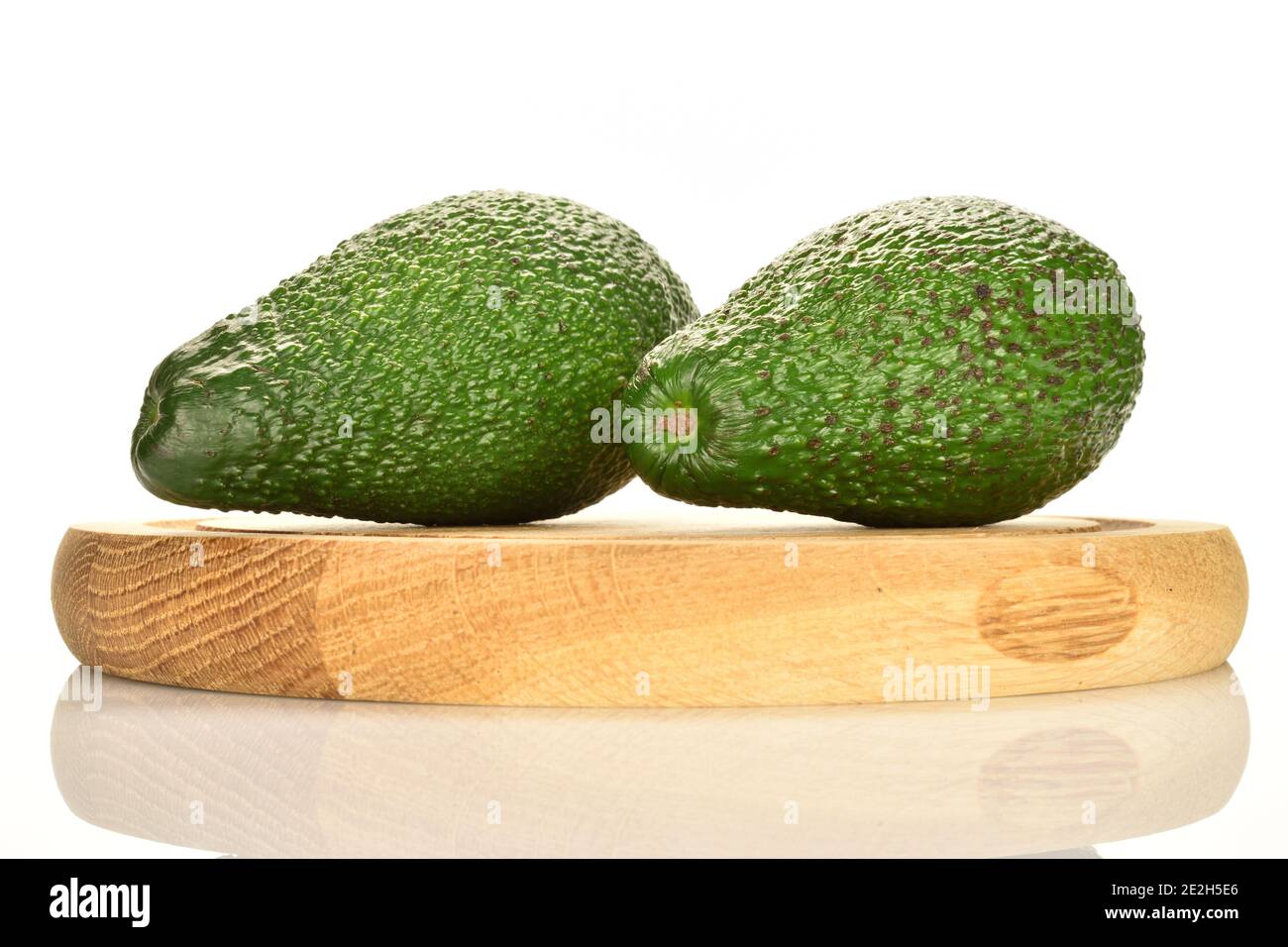 Two whole green dietary ripe avocados lying on a round stand made of ...