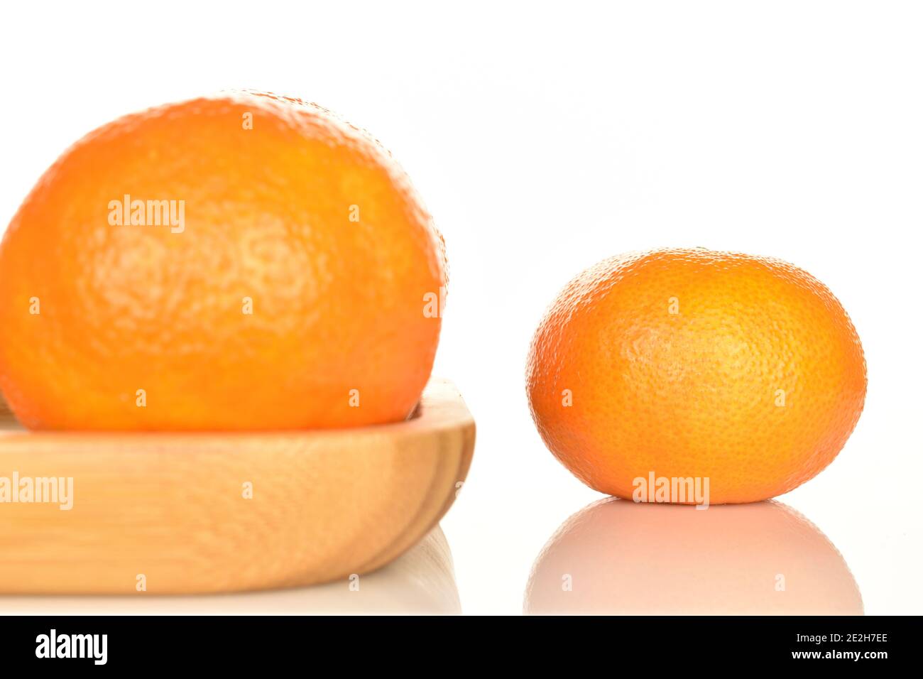 On the right is a whole bright orange ripe juicy mandarin, in focus. To ...