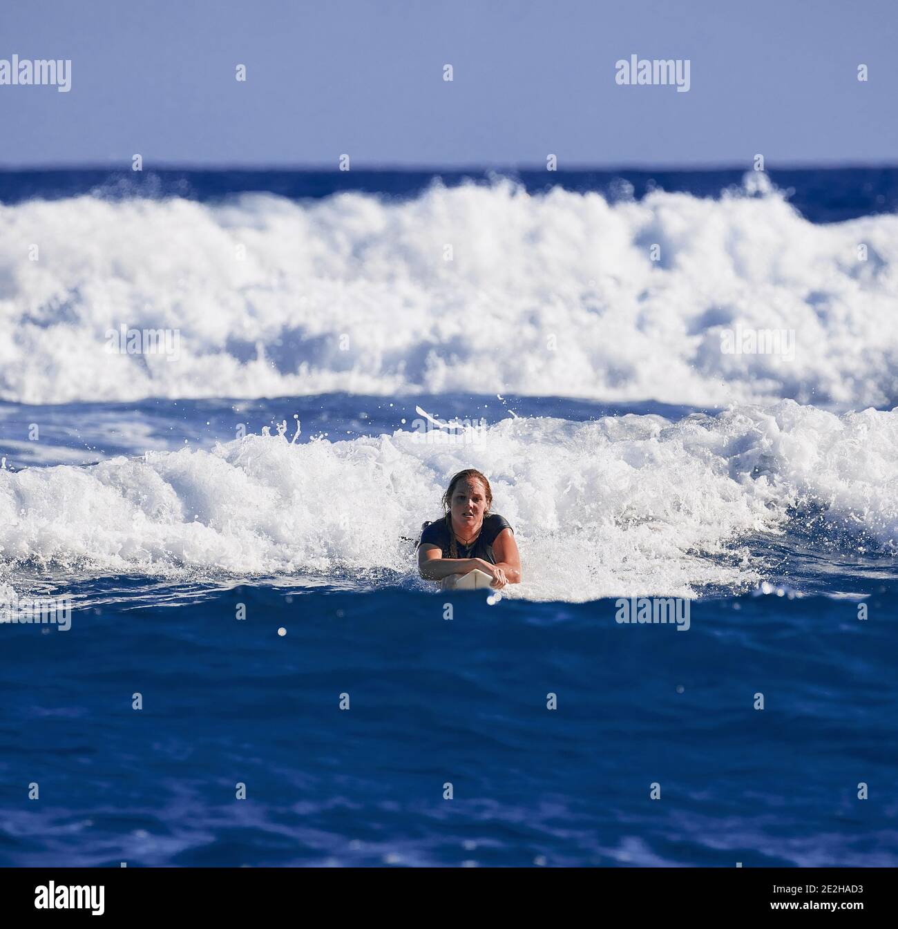 Beautiful young woman is learning to stand on a surfboard. Surf school ...
