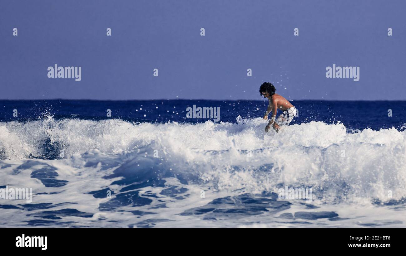 Surfer school. A young guy learning to stand on a surfboard. Surfer on ...