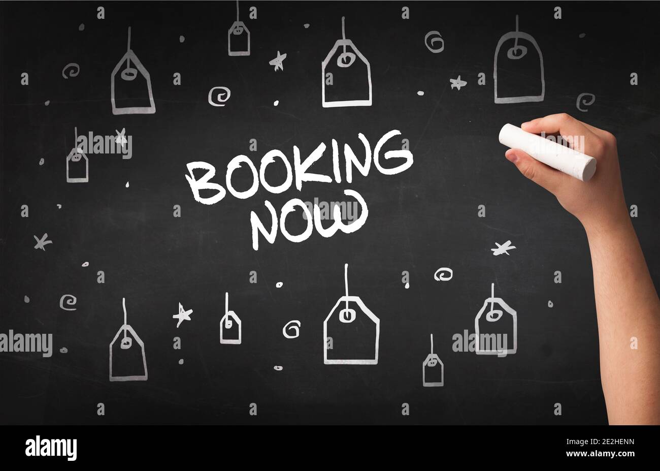 Hand drawing BOOKING NOW inscription with white chalk on blackboard ...