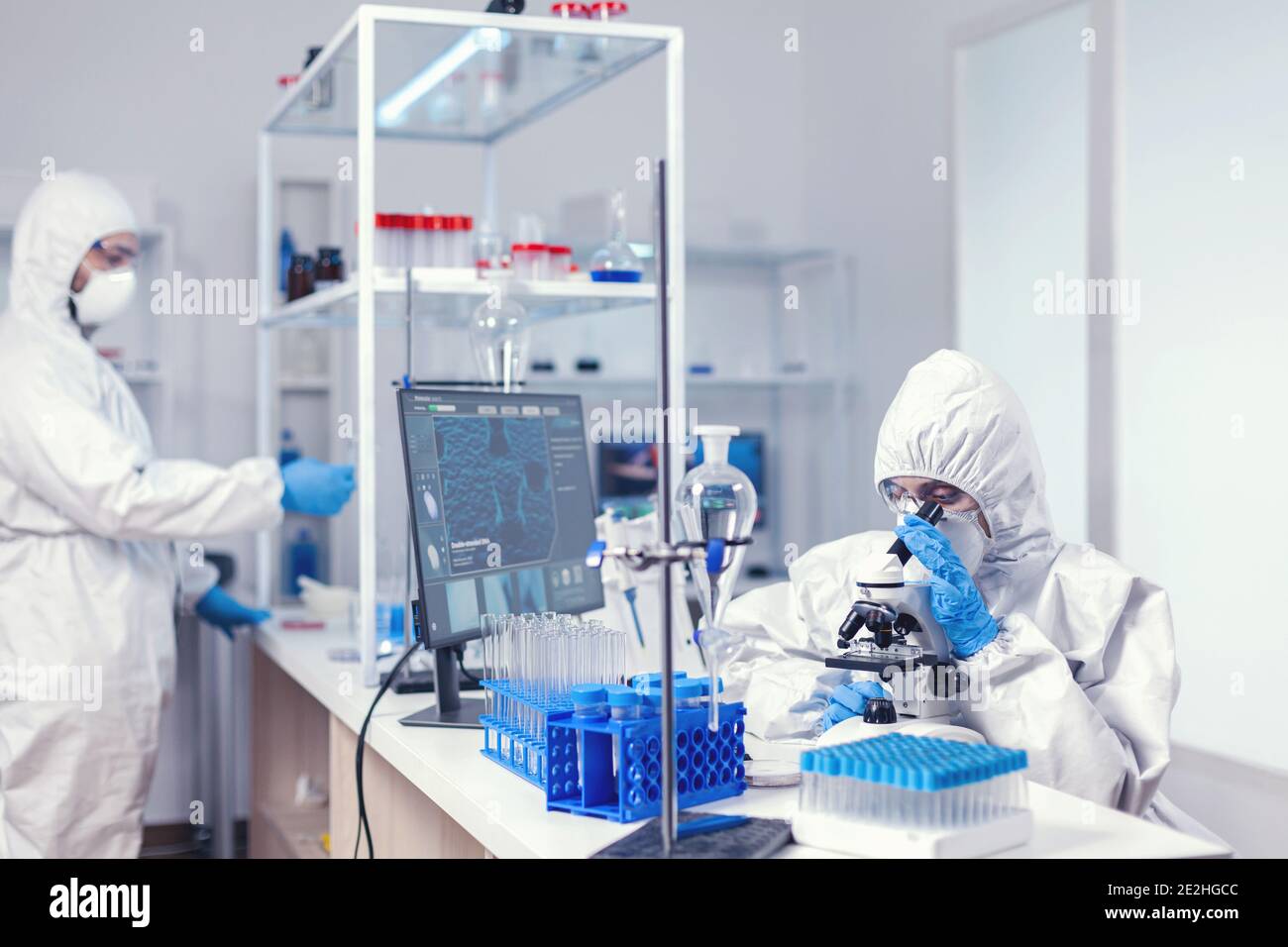 Close up of scientist using a microscope a microscope wearing ppe suit ...