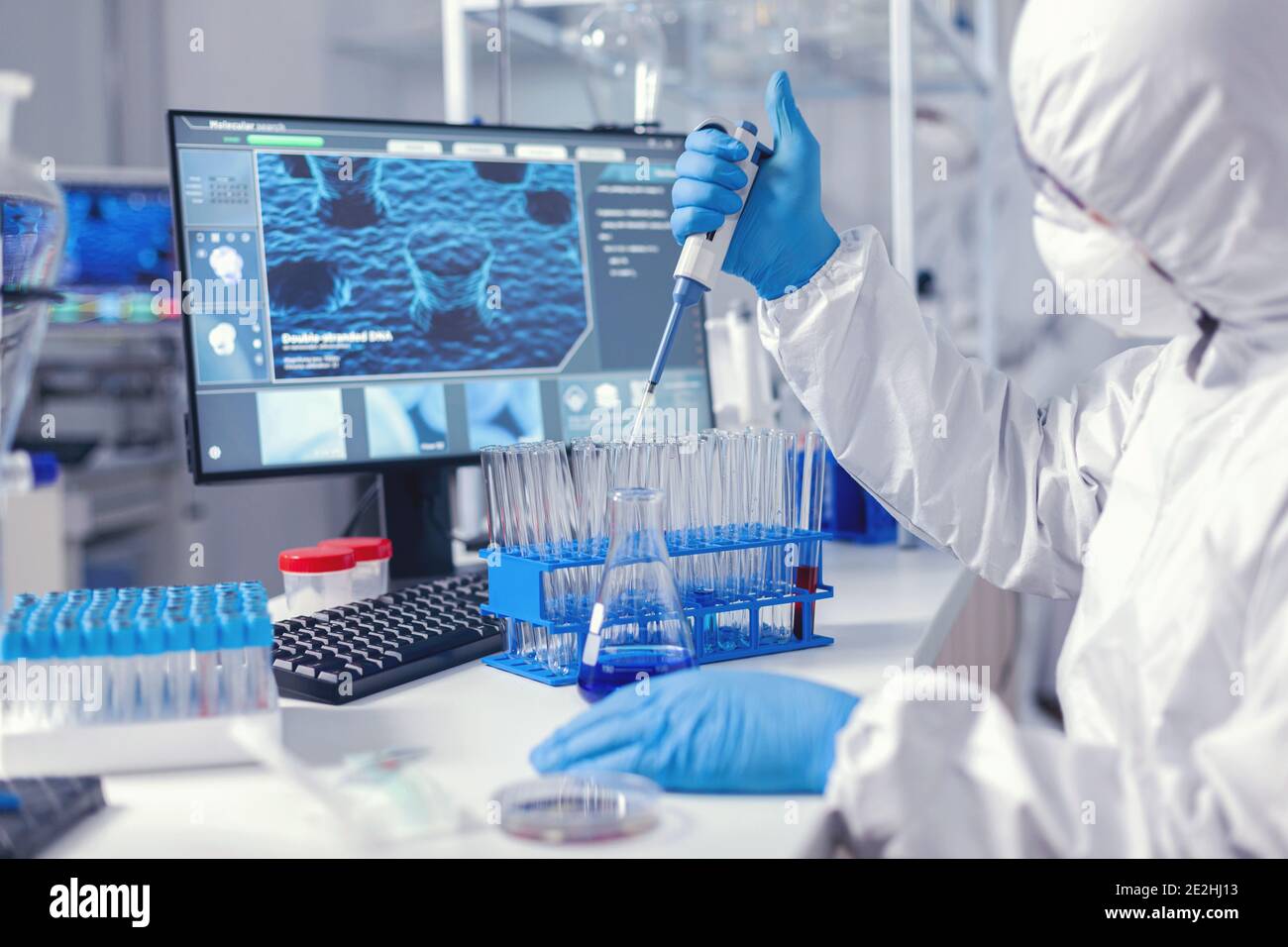 Healthcare researcher in ppe suit working with micro pipette in time of ...