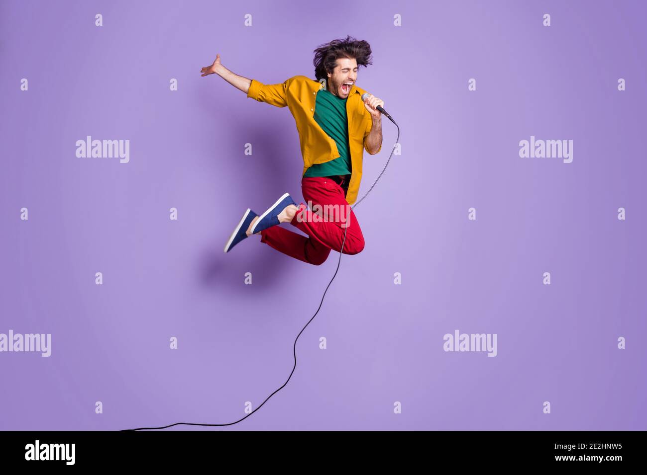 Full length photo portrait of crazy guy jumping up singing into ...
