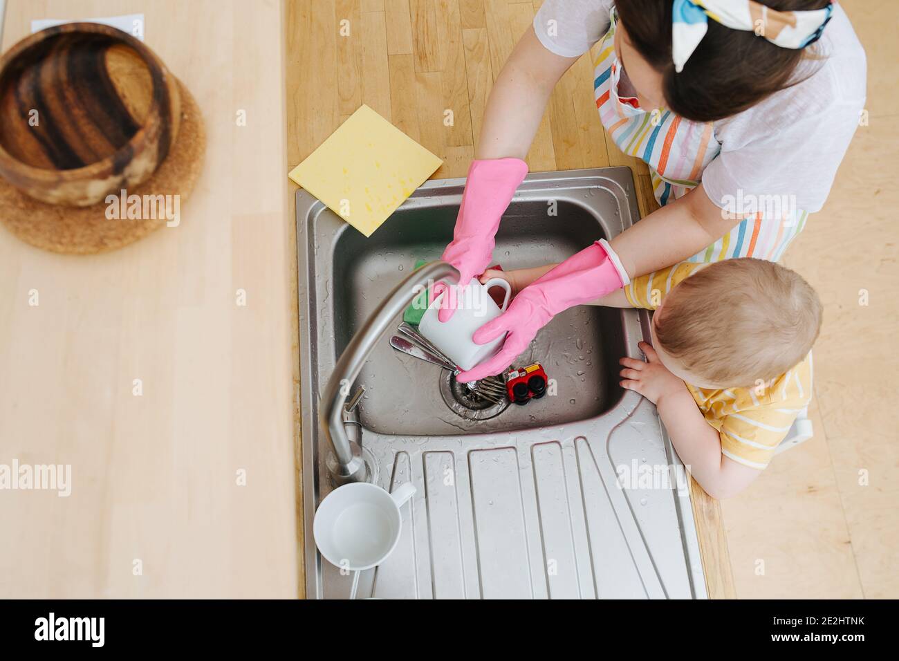 Mom washes dishes, while the son put the car in the sink Stock Photo ...