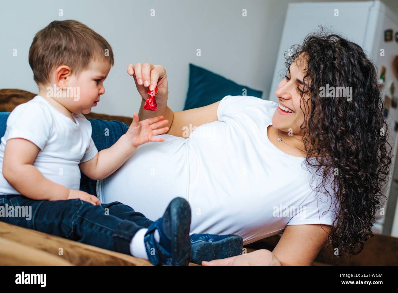 Pregnant mom giving candy to her firstborn son while playing Stock ...