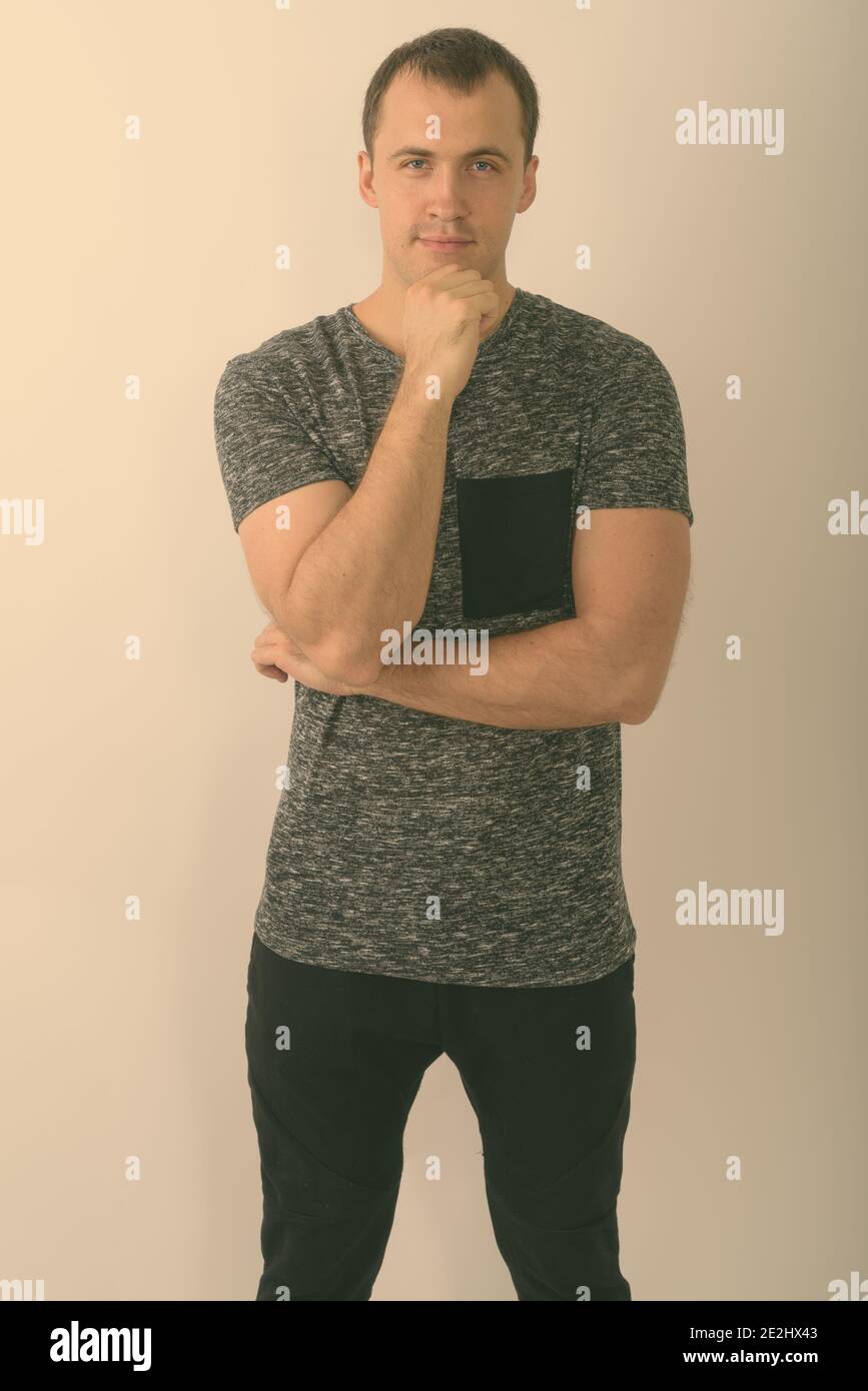 Studio shot of young muscular man standing while thinking against white ...