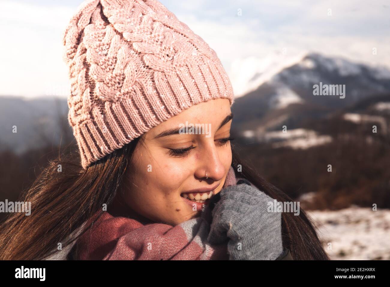 Young woman portrait on a winter landscape well wrapped up for cold ...
