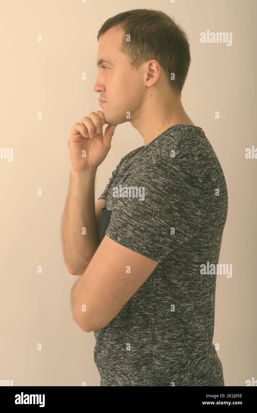 Profile view of young muscular man thinking against white background ...
