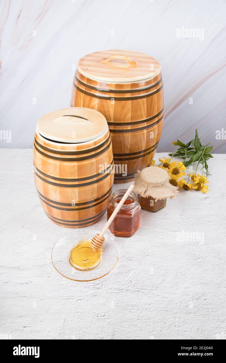 Two ceramic barrels and two glass jars with honey and a saucer with ...