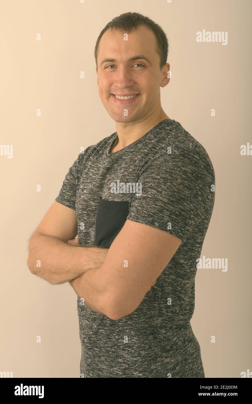 Studio shot of young happy muscular man smiling with arms crossed ...