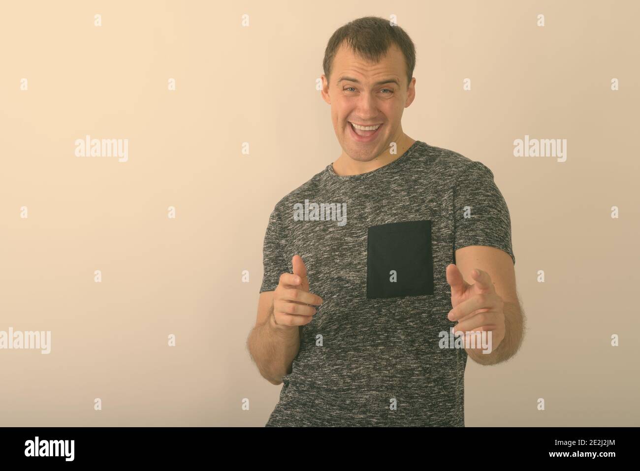 Studio shot of young happy muscular man smiling while pointing both ...