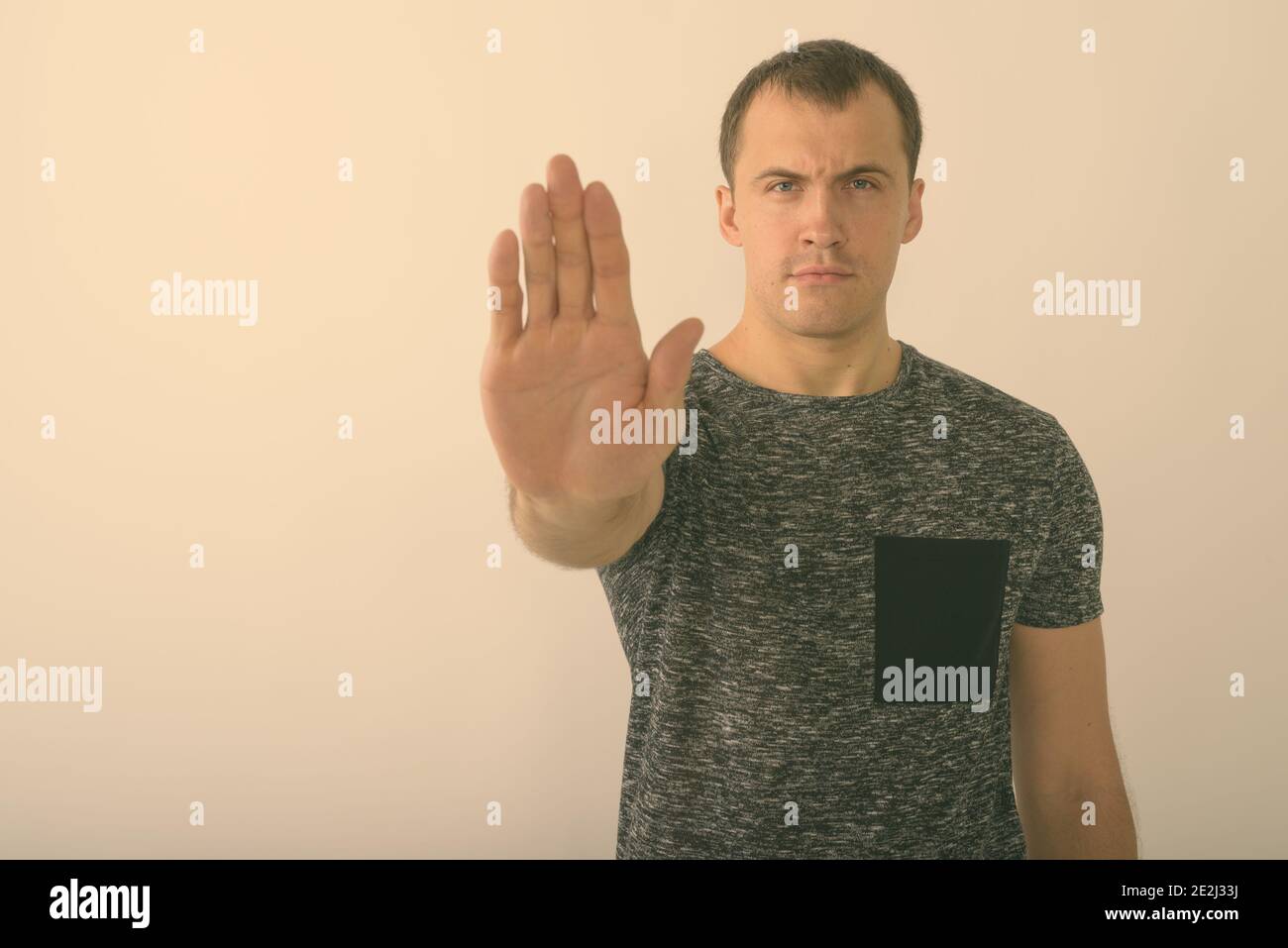 Studio shot of angry young muscular man showing stop hand sign against ...