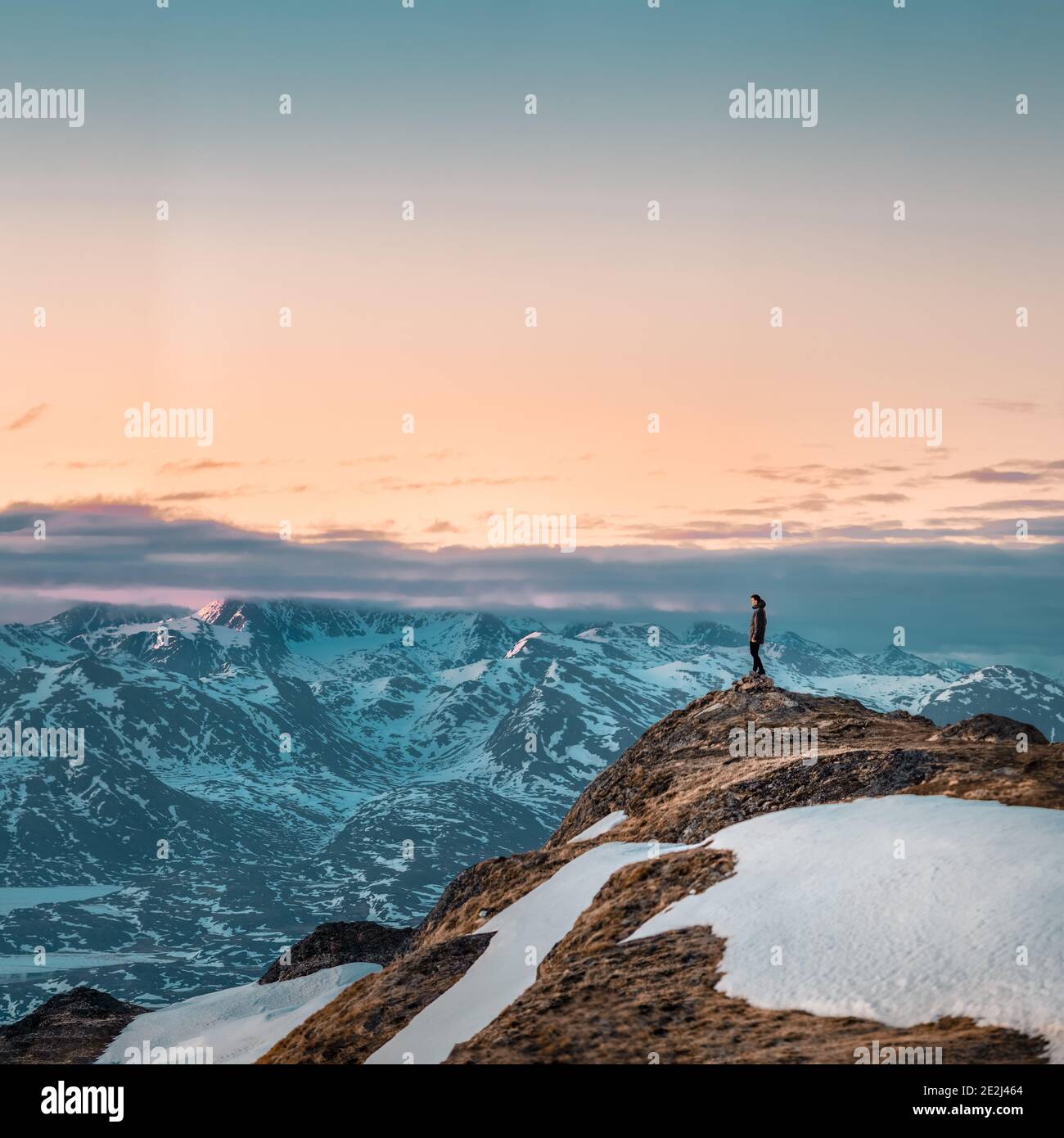 Mesmerizing shot of a male standing on the top of rock under the gloomy ...