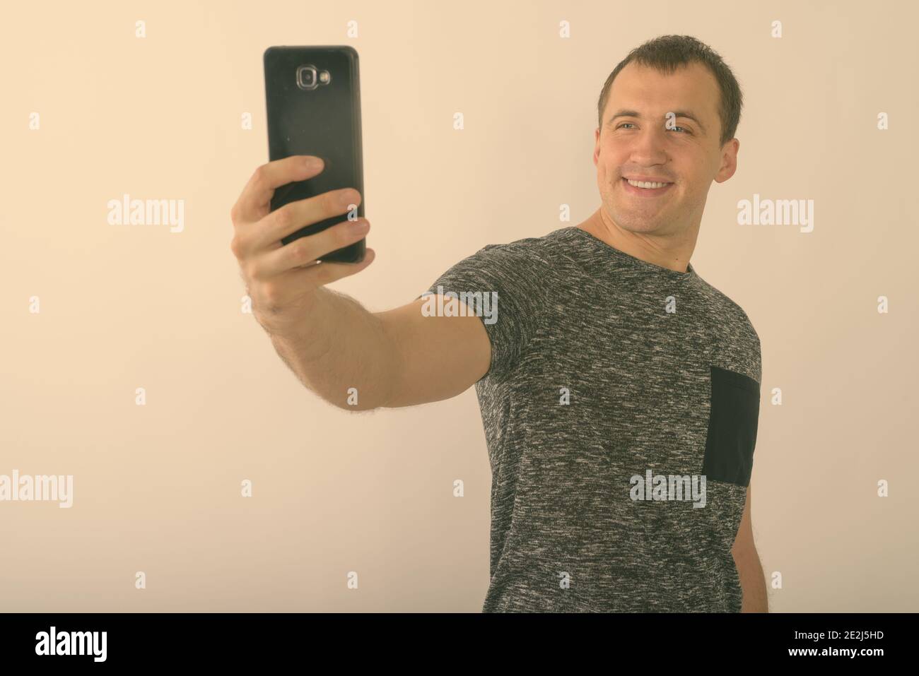 Studio shot of young happy muscular man smiling while taking selfie ...