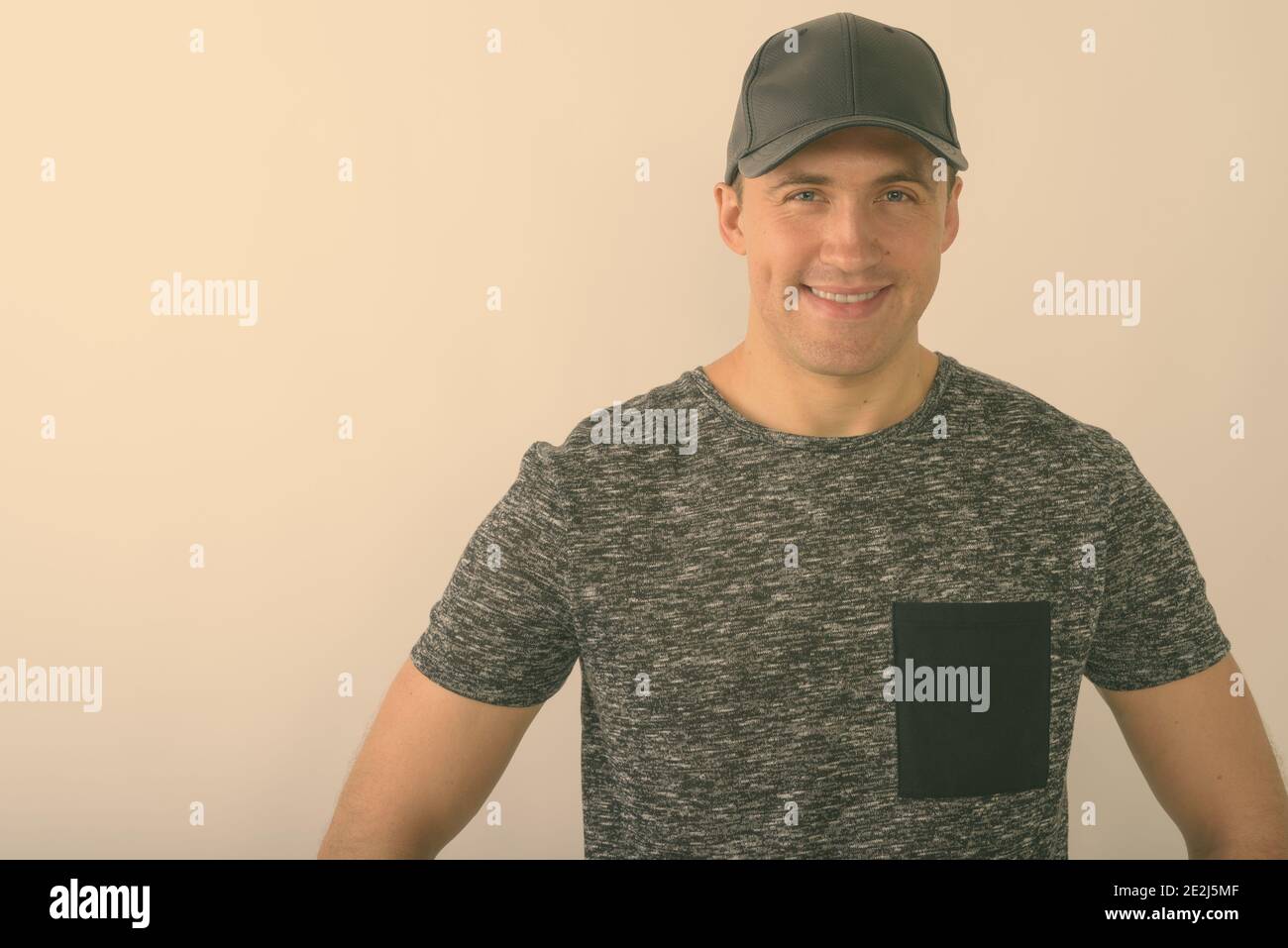 Close up of young happy muscular man smiling while wearing cap against ...