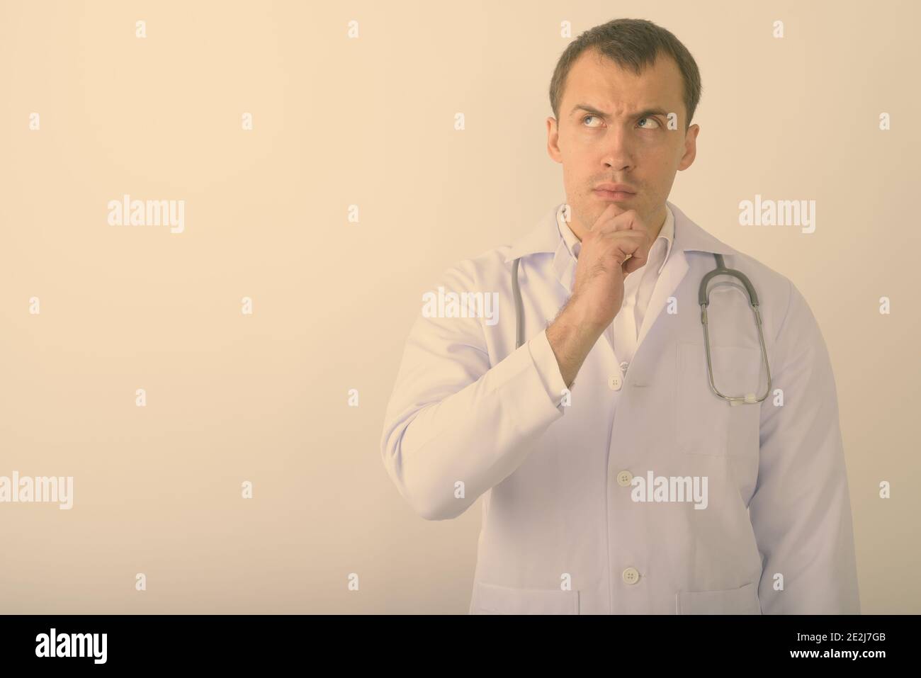 Studio shot of young muscular man doctor thinking while looking up ...