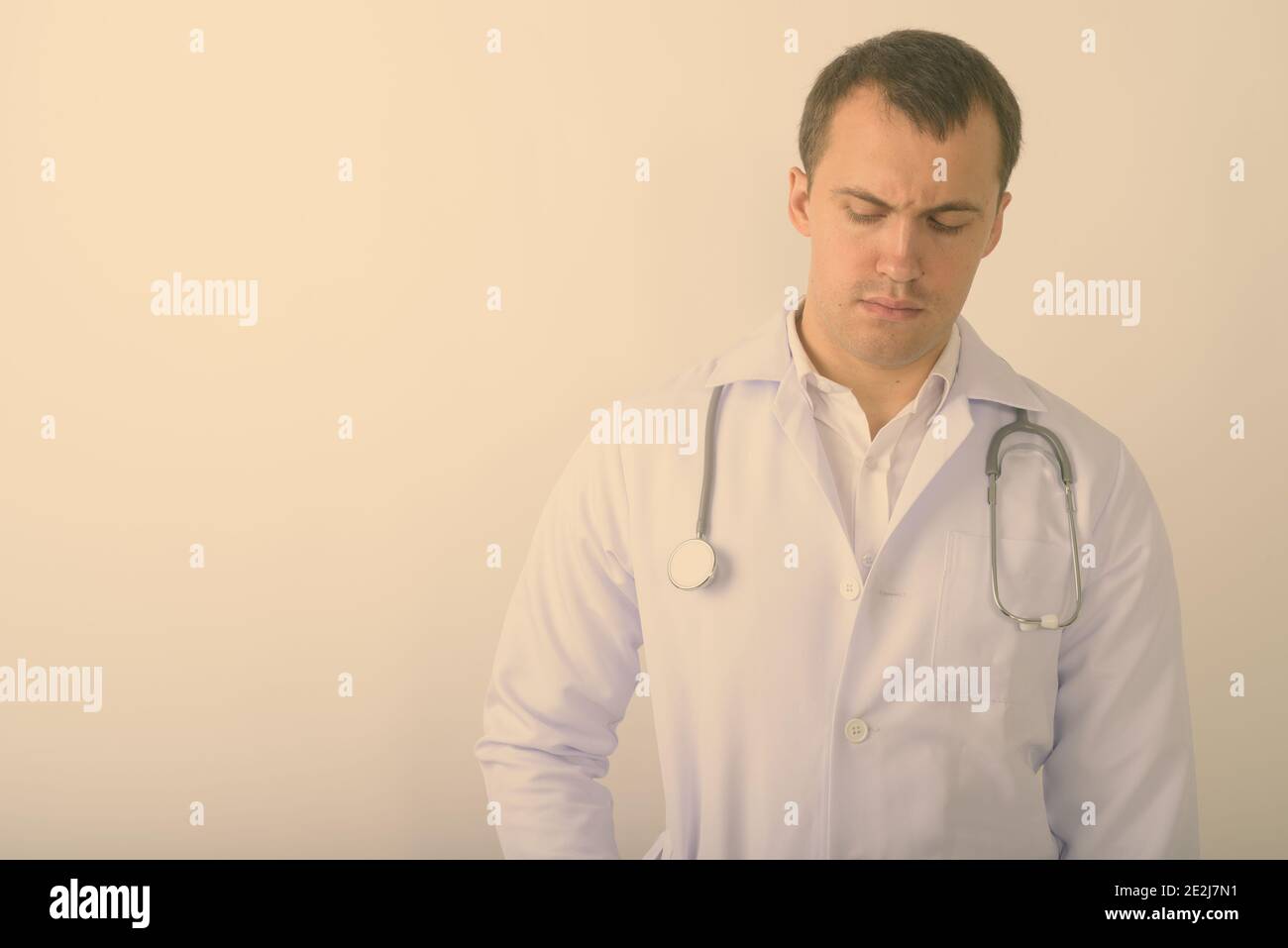Studio shot of young muscular man doctor thinking while looking down ...