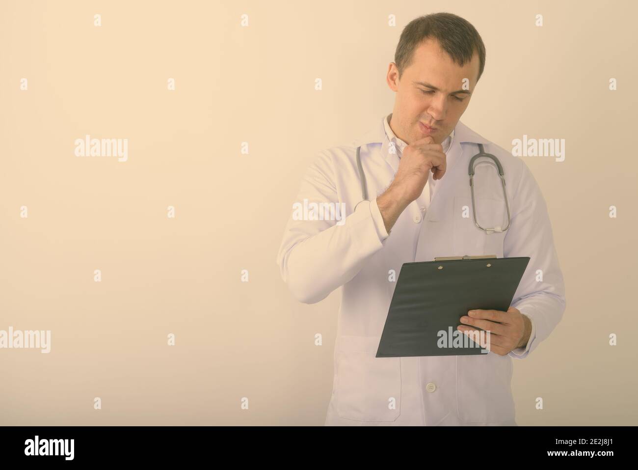Studio shot of young muscular man doctor thinking while reading on ...