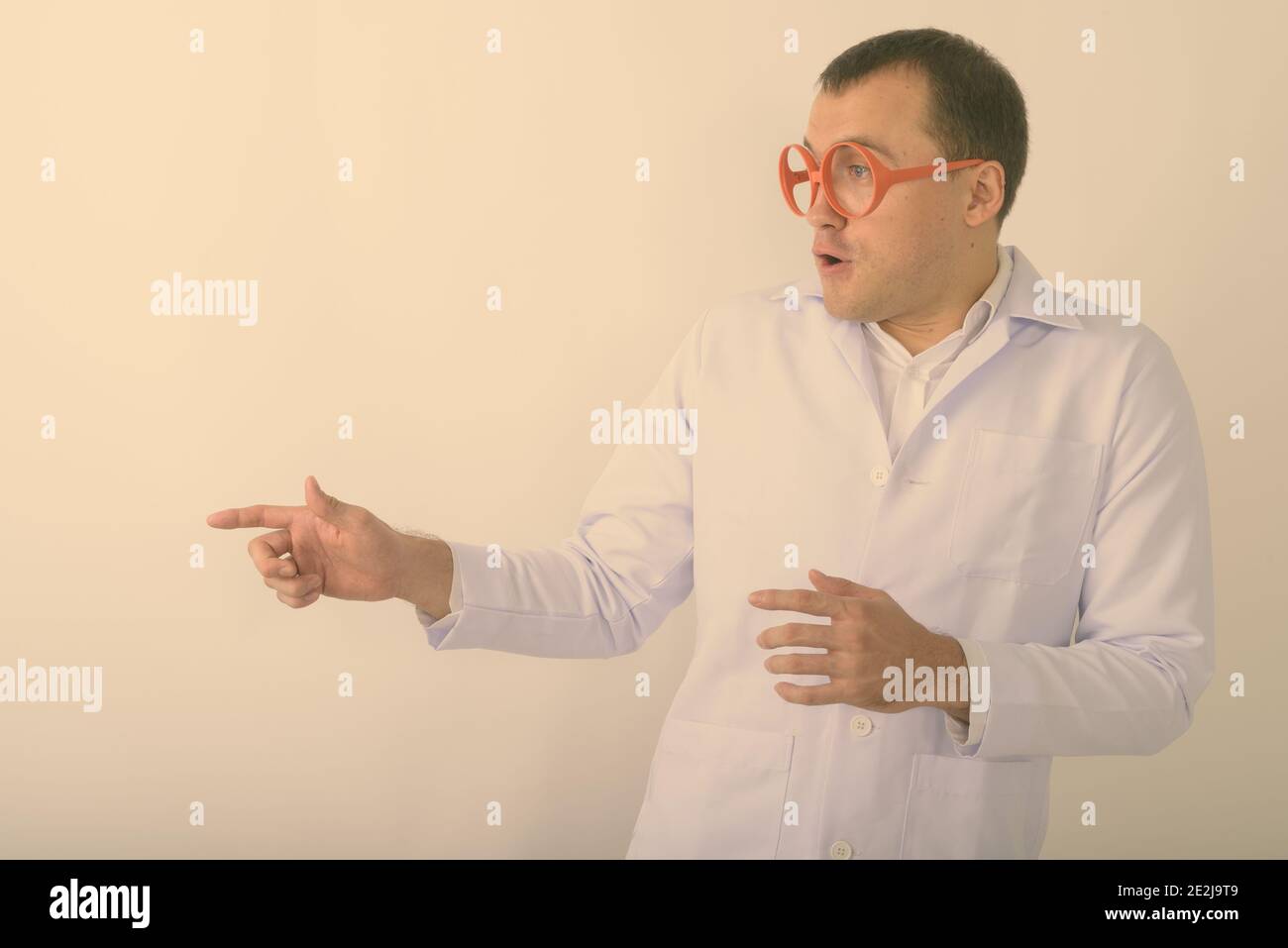 Studio shot of young muscular man doctor pointing to the side while ...