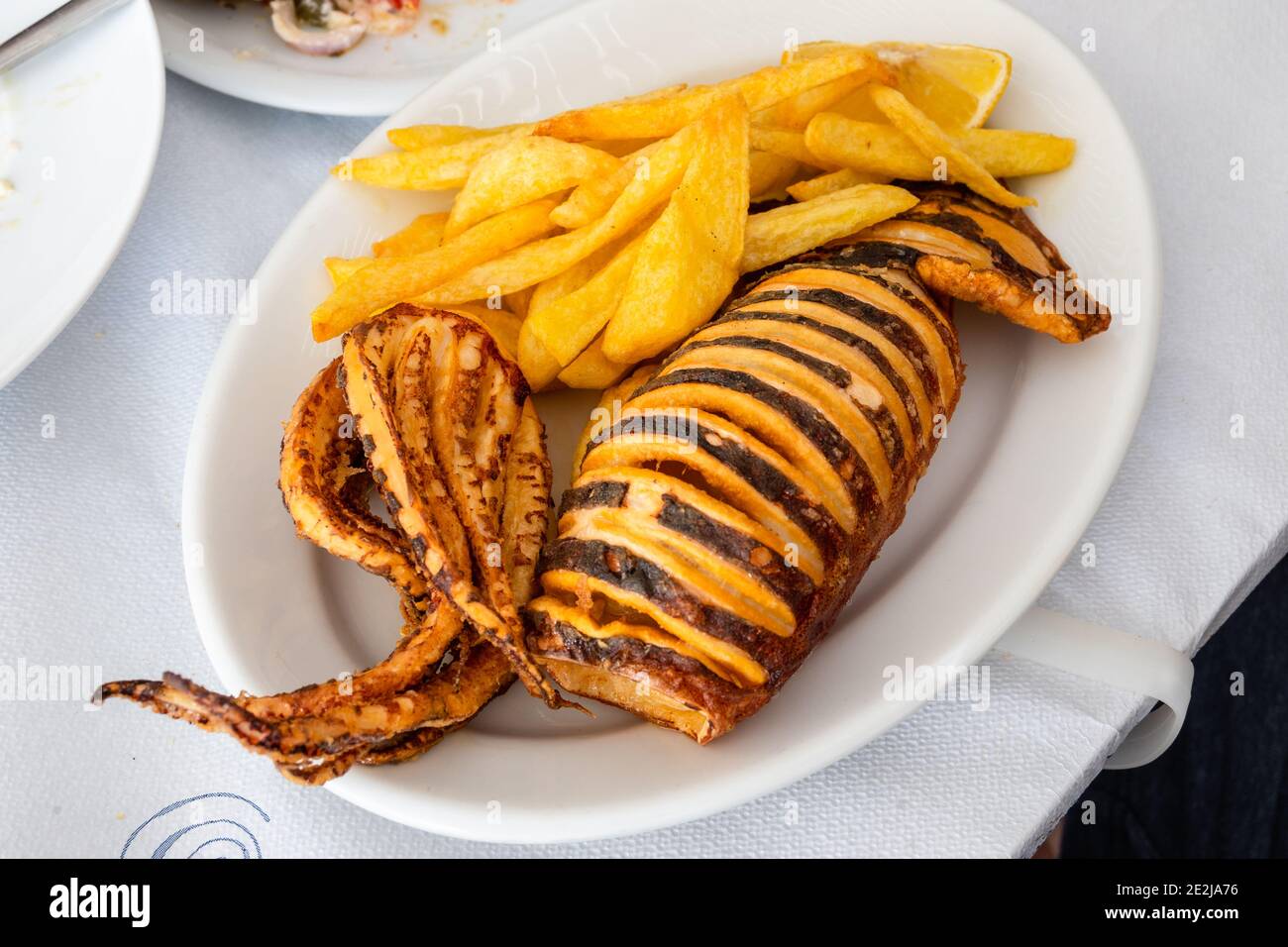 Grilled squid served with fries. Traditional Greek dish Stock Photo - Alamy