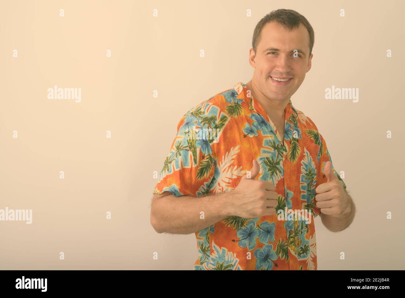 Studio shot of young happy muscular tourist man smiling while giving ...