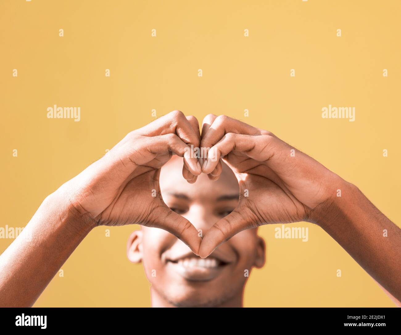 Happy Afro American showing heart sign on a yellow background Stock ...