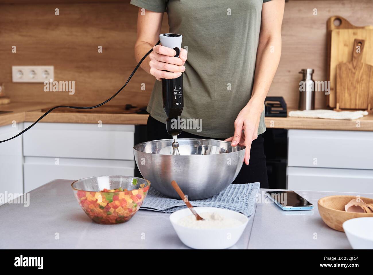 Woman in the kitchen cooking a cake. Hands beat the dough with an ...