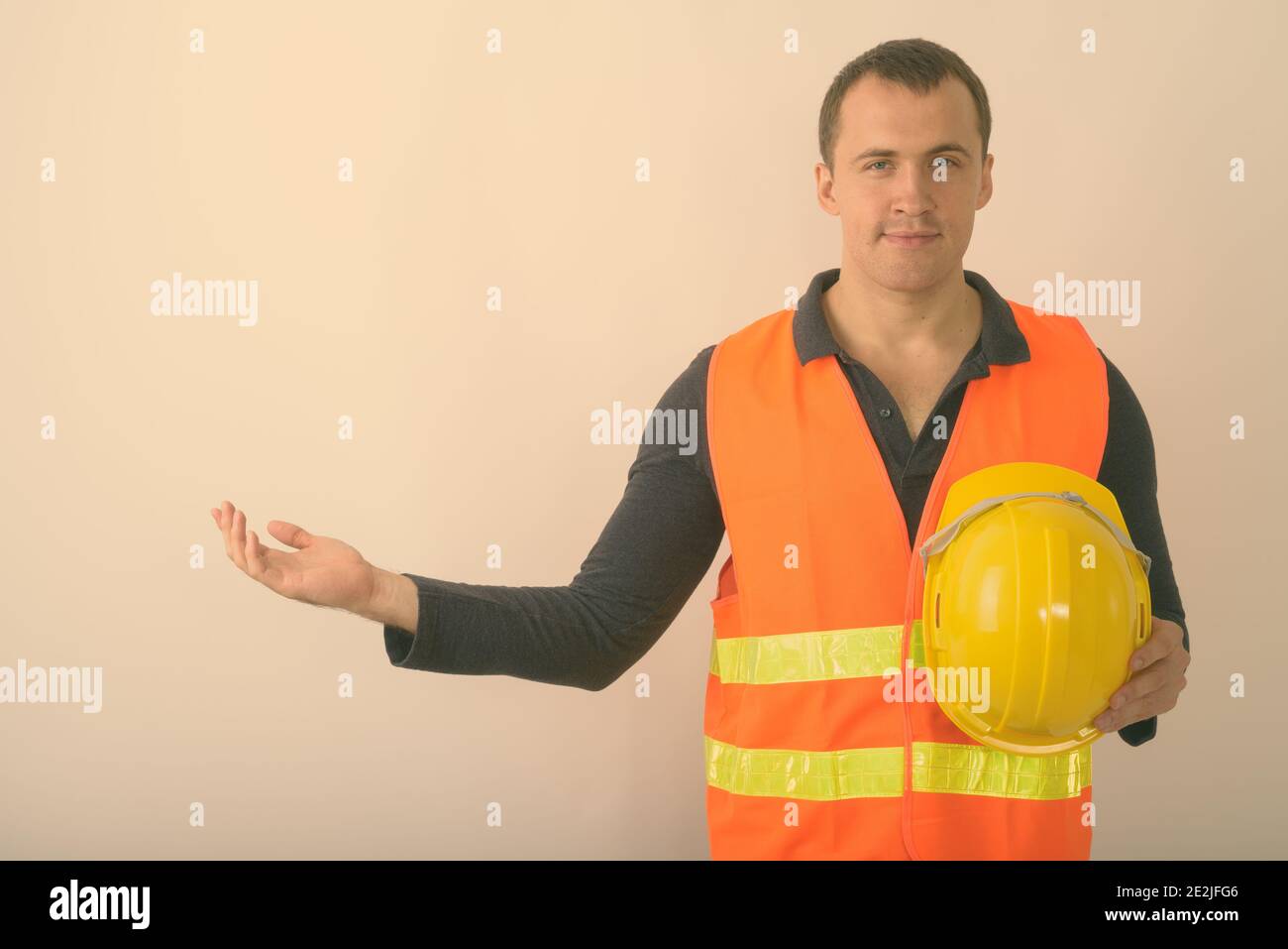 Studio shot of young muscular man construction worker holding safety ...