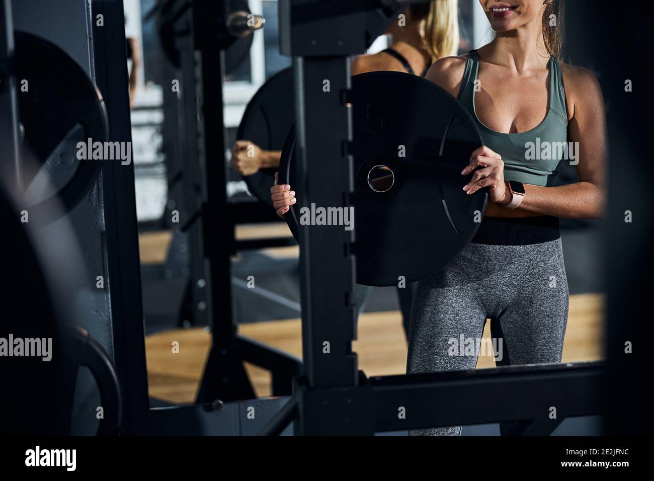Female weightlifter pulling off a disk weight Stock Photo - Alamy