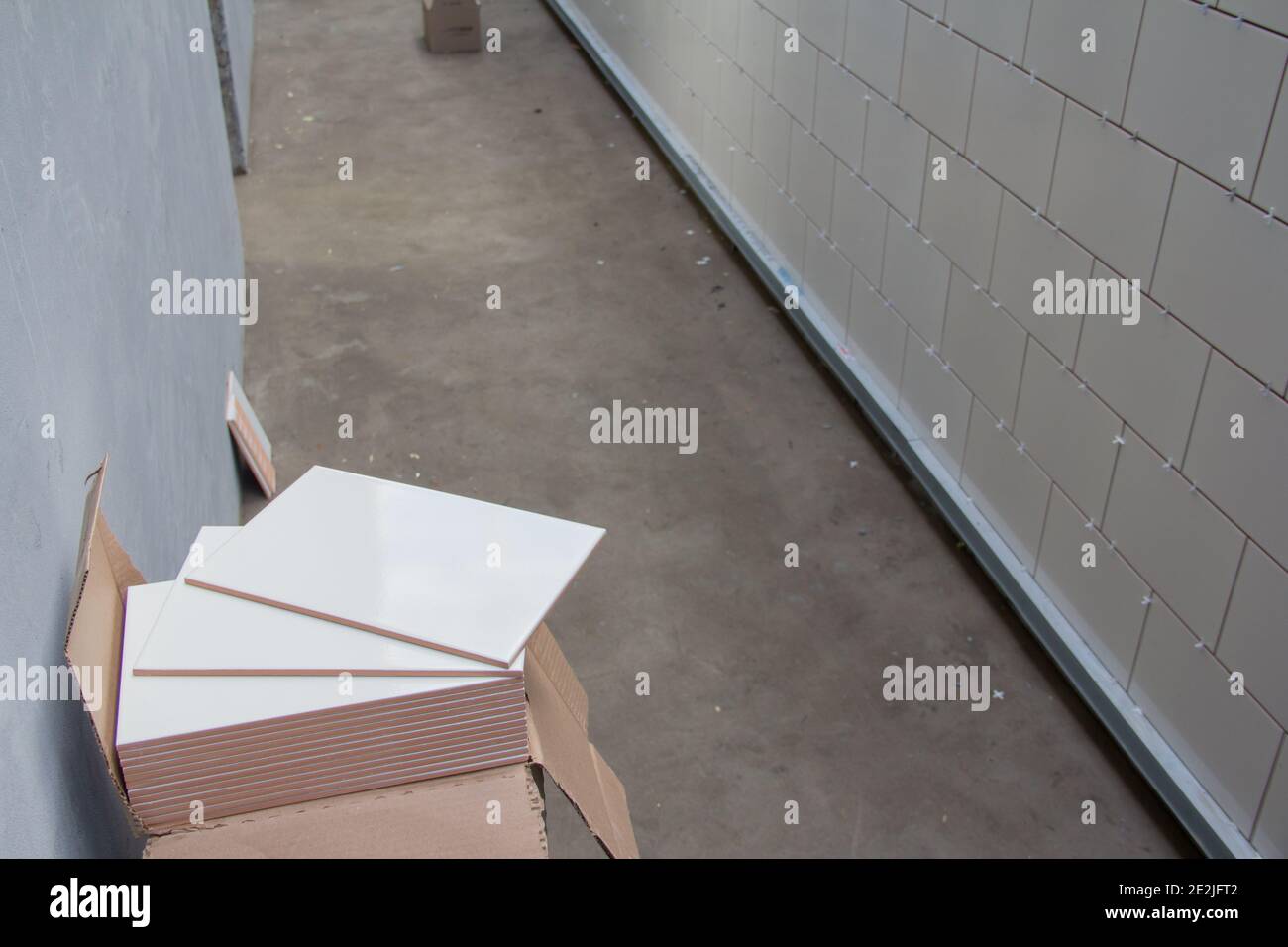 Laying Ceramic Tiles on the wall. White ceramic tiles. Renovation work ...