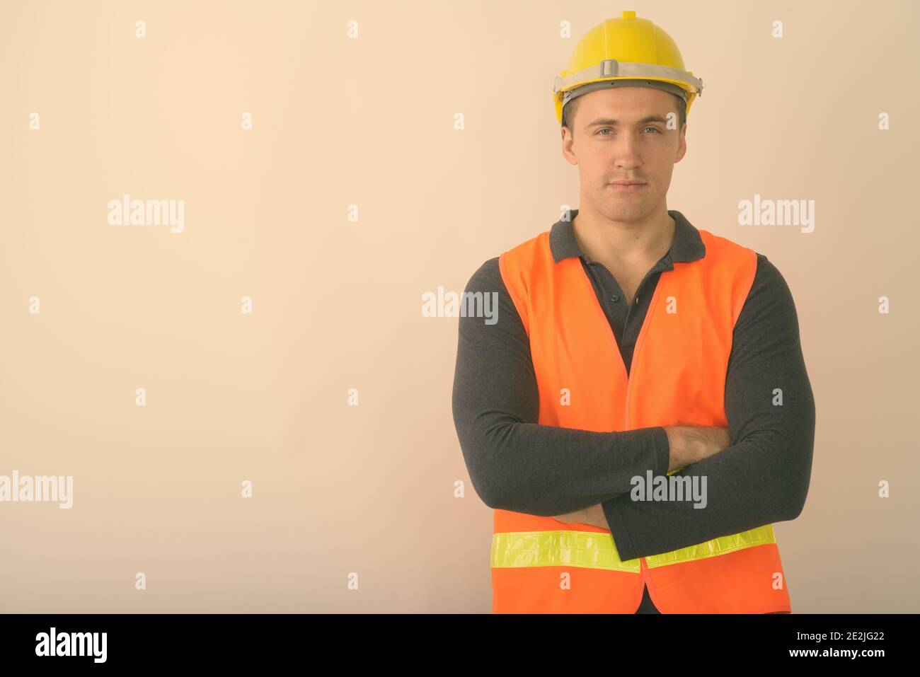 Studio shot of young muscular man construction worker with arms crossed ...