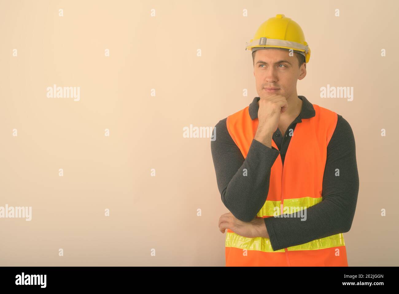 Studio shot of young muscular man construction worker thinking against ...