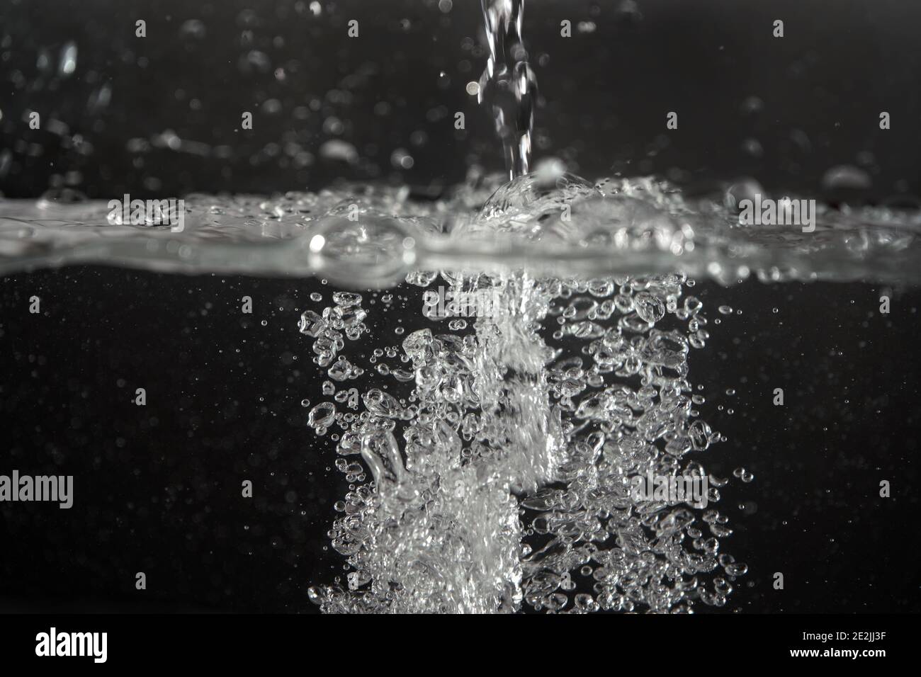 Water splashing as it's poured into aquarium tank, black background ...
