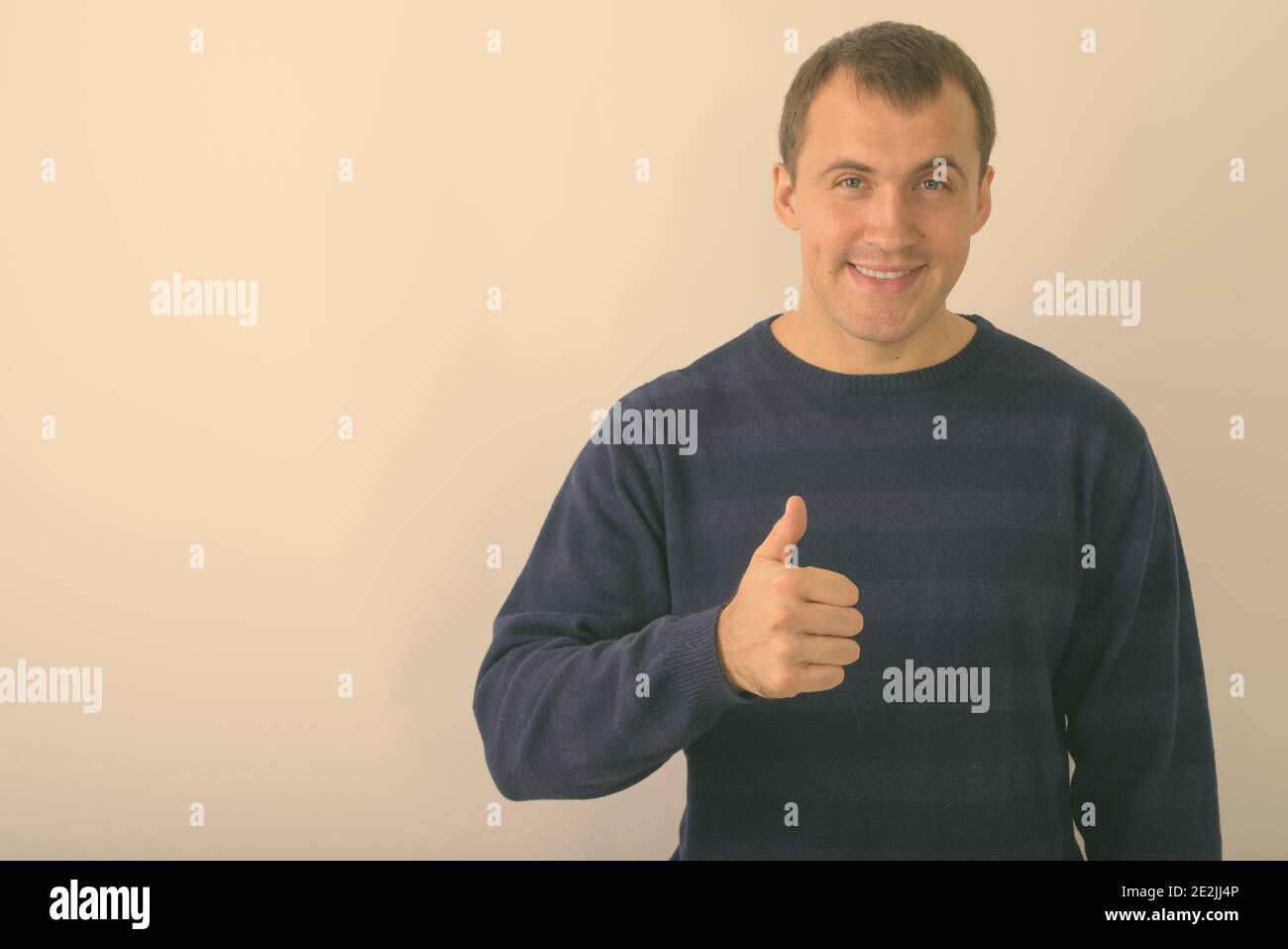 Studio shot of young happy muscular man smiling while giving thumb up ...