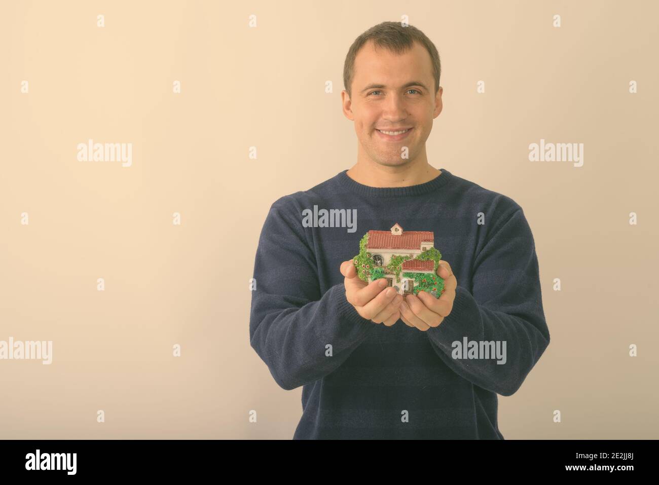 Studio shot of young happy muscular man smiling while holding house ...