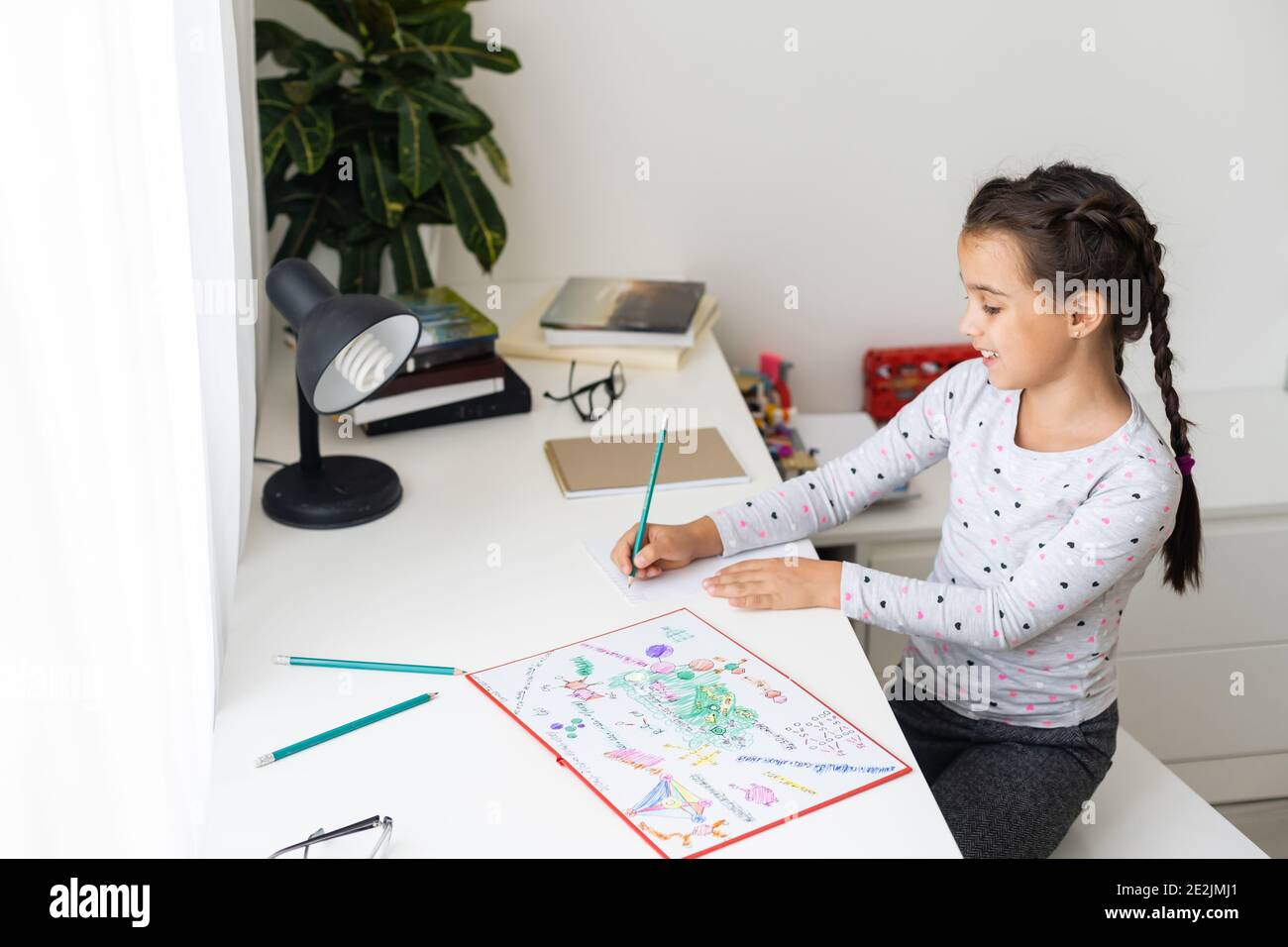 cute happy little girl writing something in her notebook Stock Photo ...