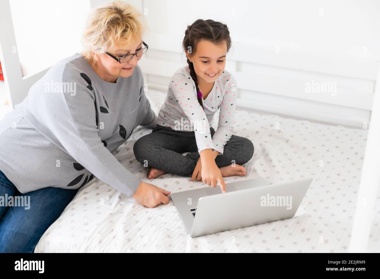 Cute and happy little girl child using laptop computer with her grandma ...