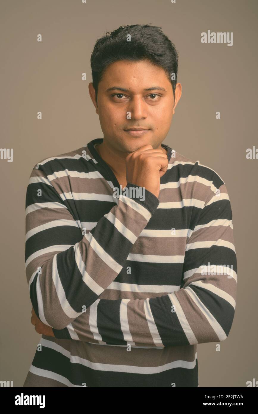 Young Indian man against gray background Stock Photo - Alamy