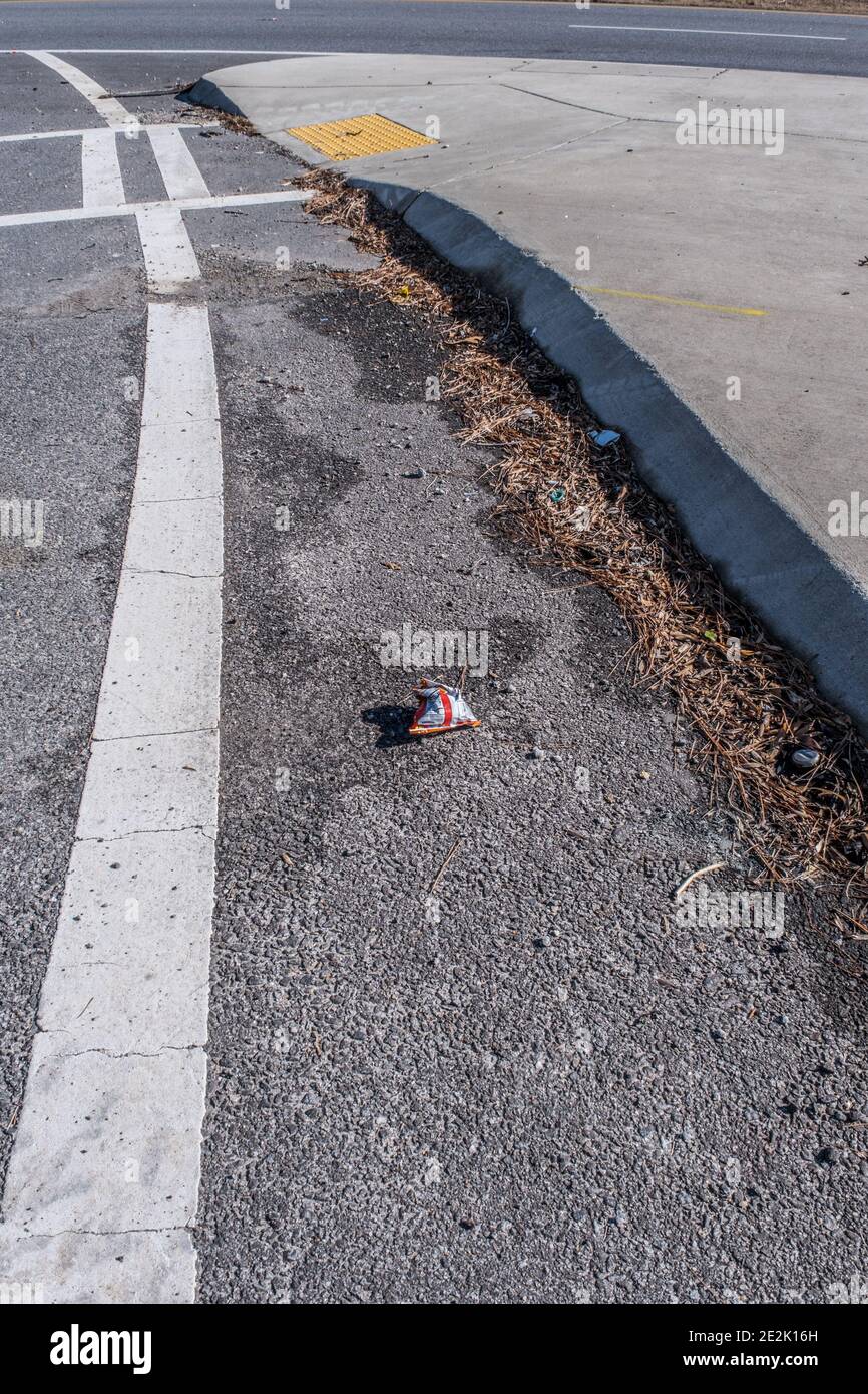 Discarded snack chips bag laying alongside the curb in the roadway ...