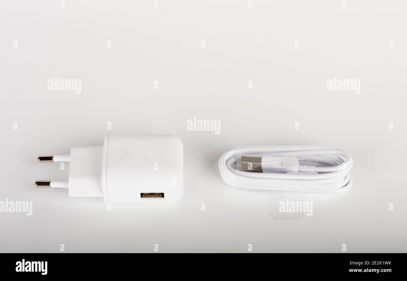 White charger and white cable for charging of smartphone in white ...