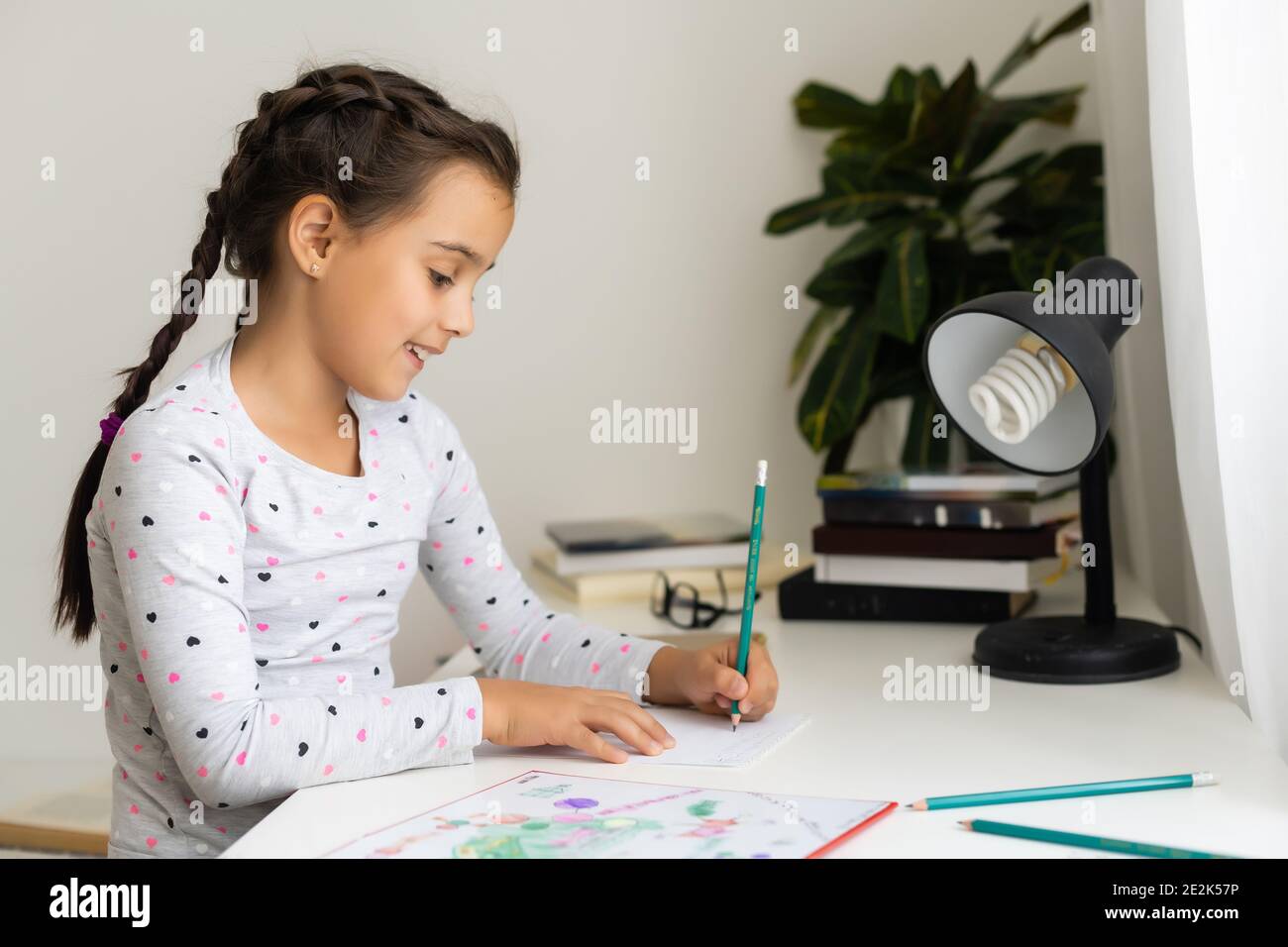 cute happy little girl writing something in her notebook Stock Photo ...