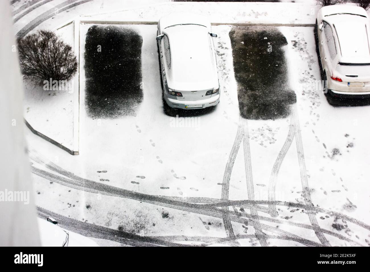 Cars covered with snow in the parking lot, winter, tire tracks, view ...