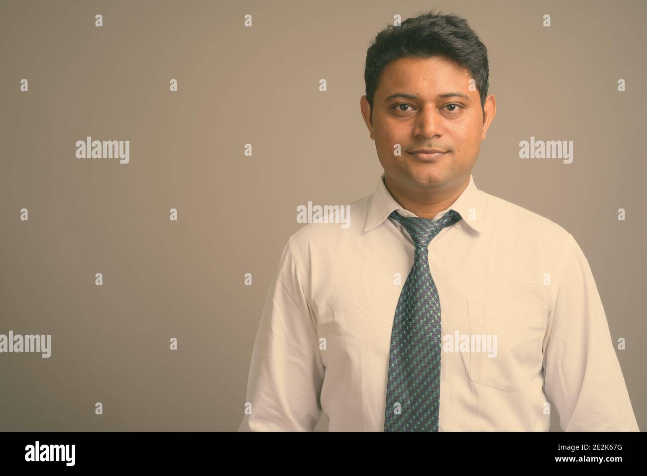 Young Indian businessman against gray background Stock Photo - Alamy