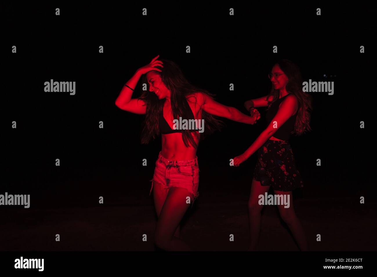 Group of young women having fun at a lakeside party at night with a red ...