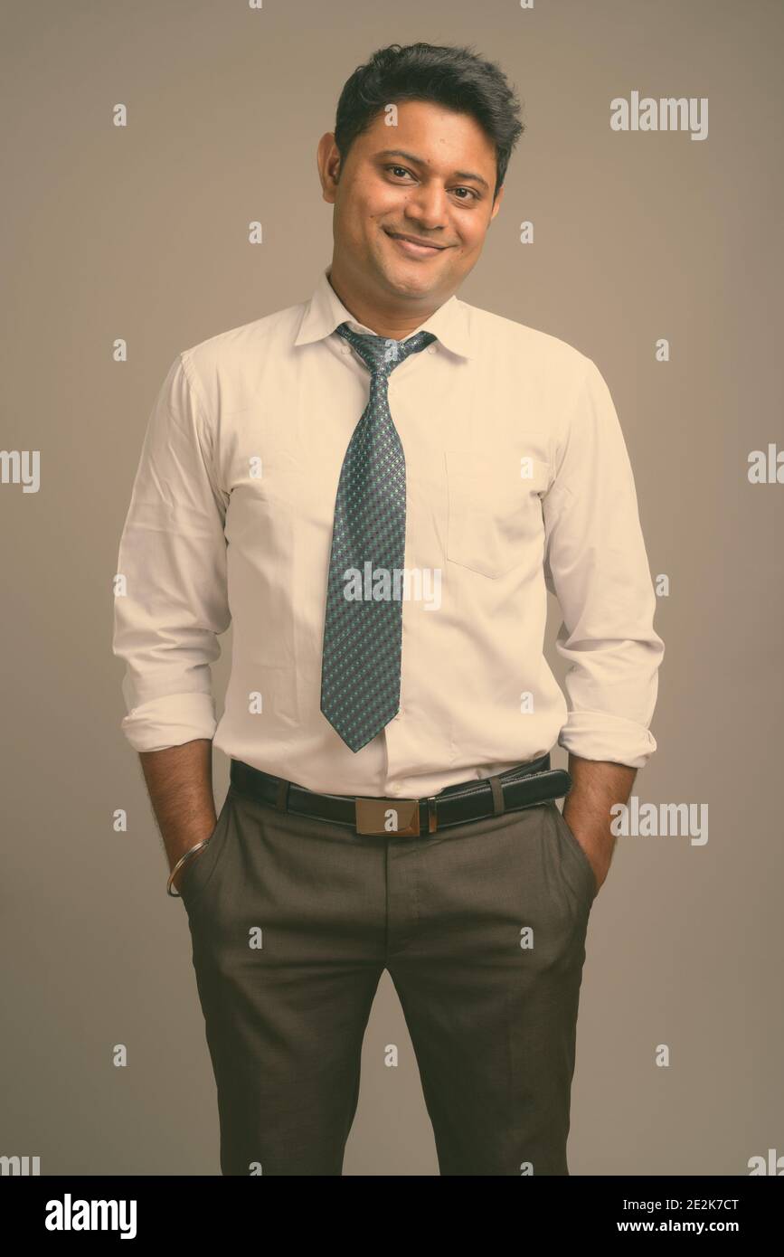 Young Indian businessman against gray background Stock Photo - Alamy