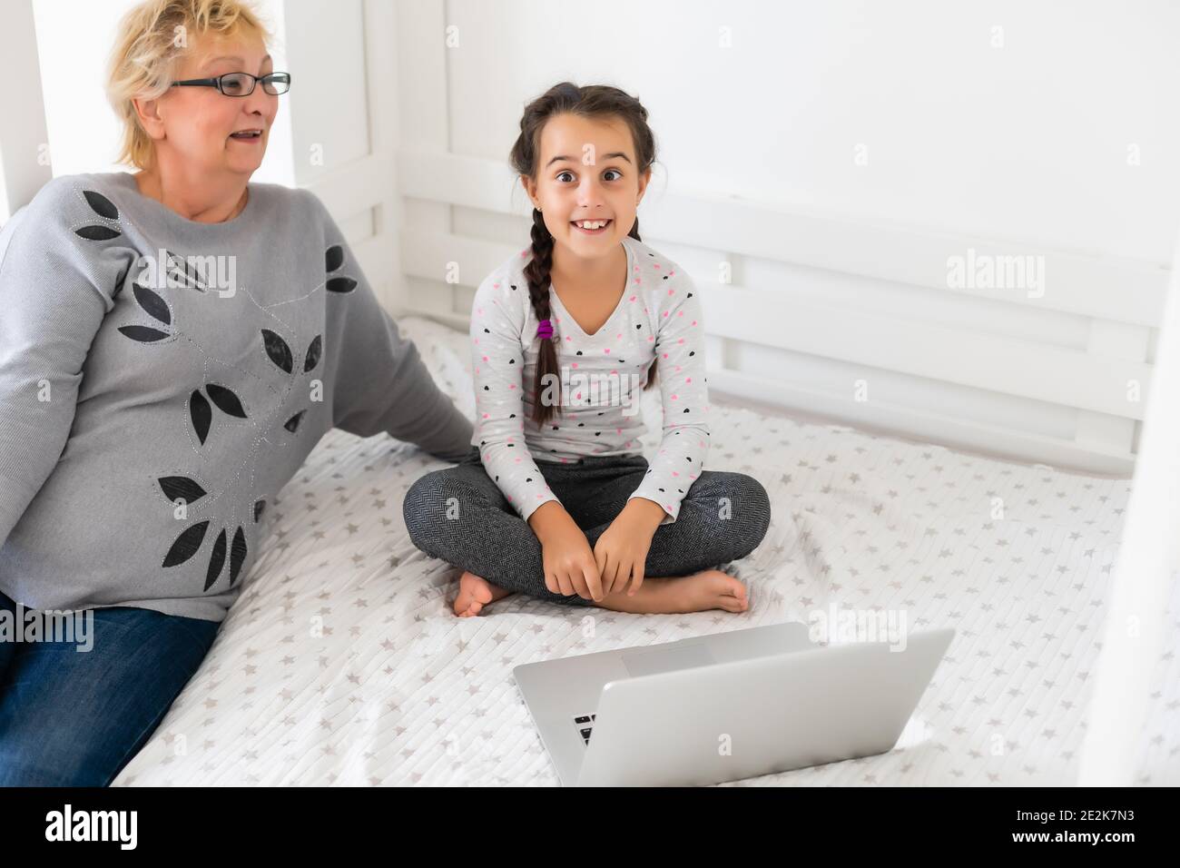 Cute and happy little girl child using laptop computer with her grandma ...